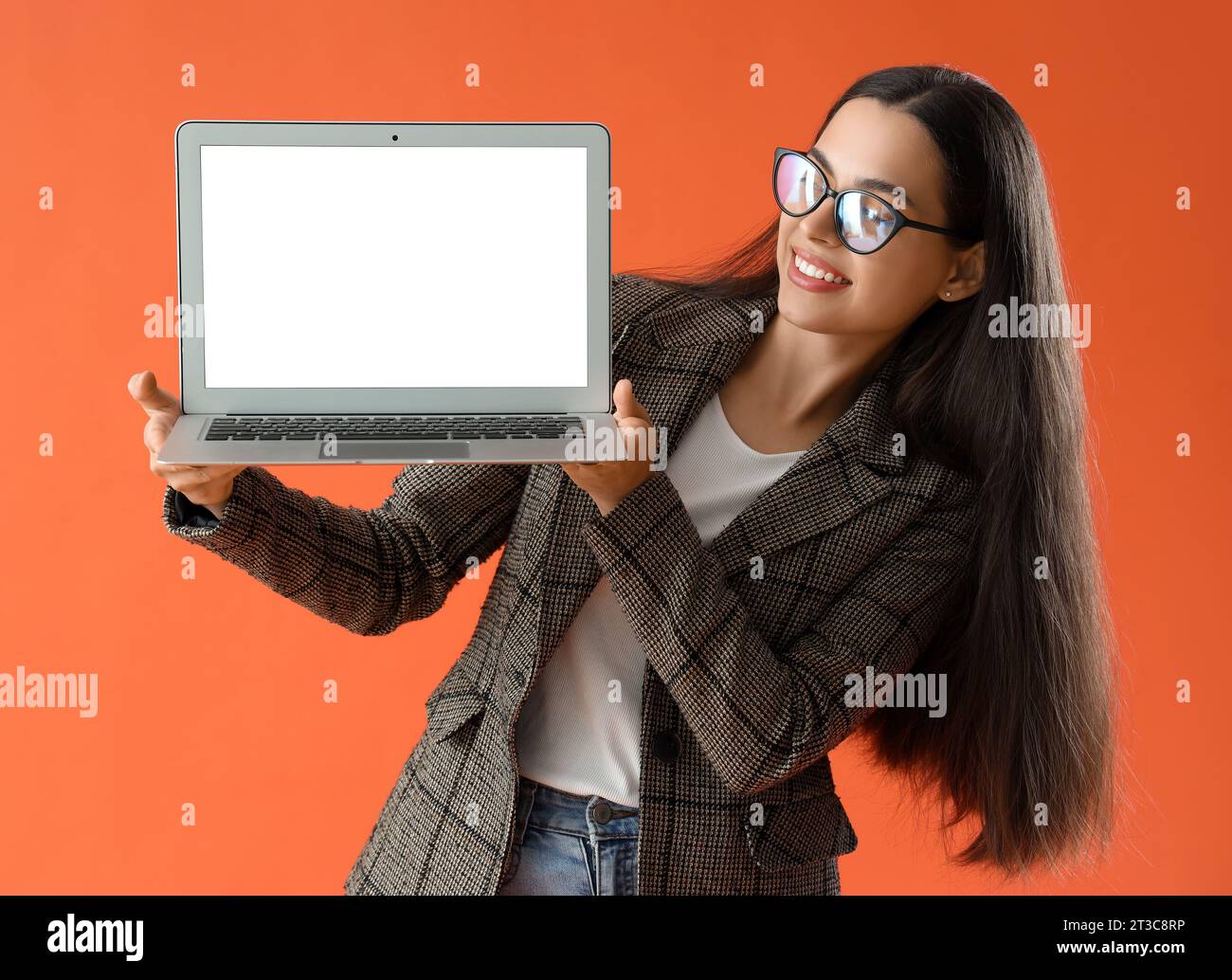 Pretty young female programmer holding laptop with blank screen on ...