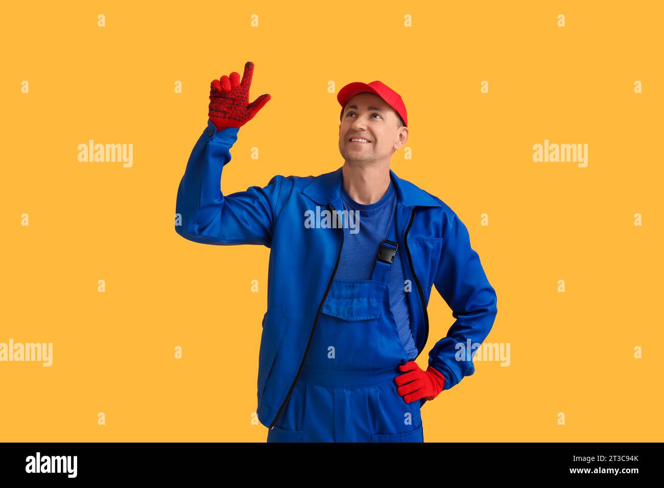 Portrait of male mechanic pointing up on orange background Stock Photo ...
