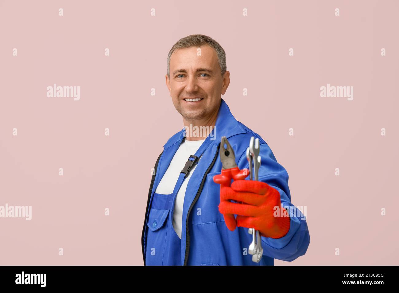 Portrait of male mechanic with tools on pink background Stock Photo - Alamy