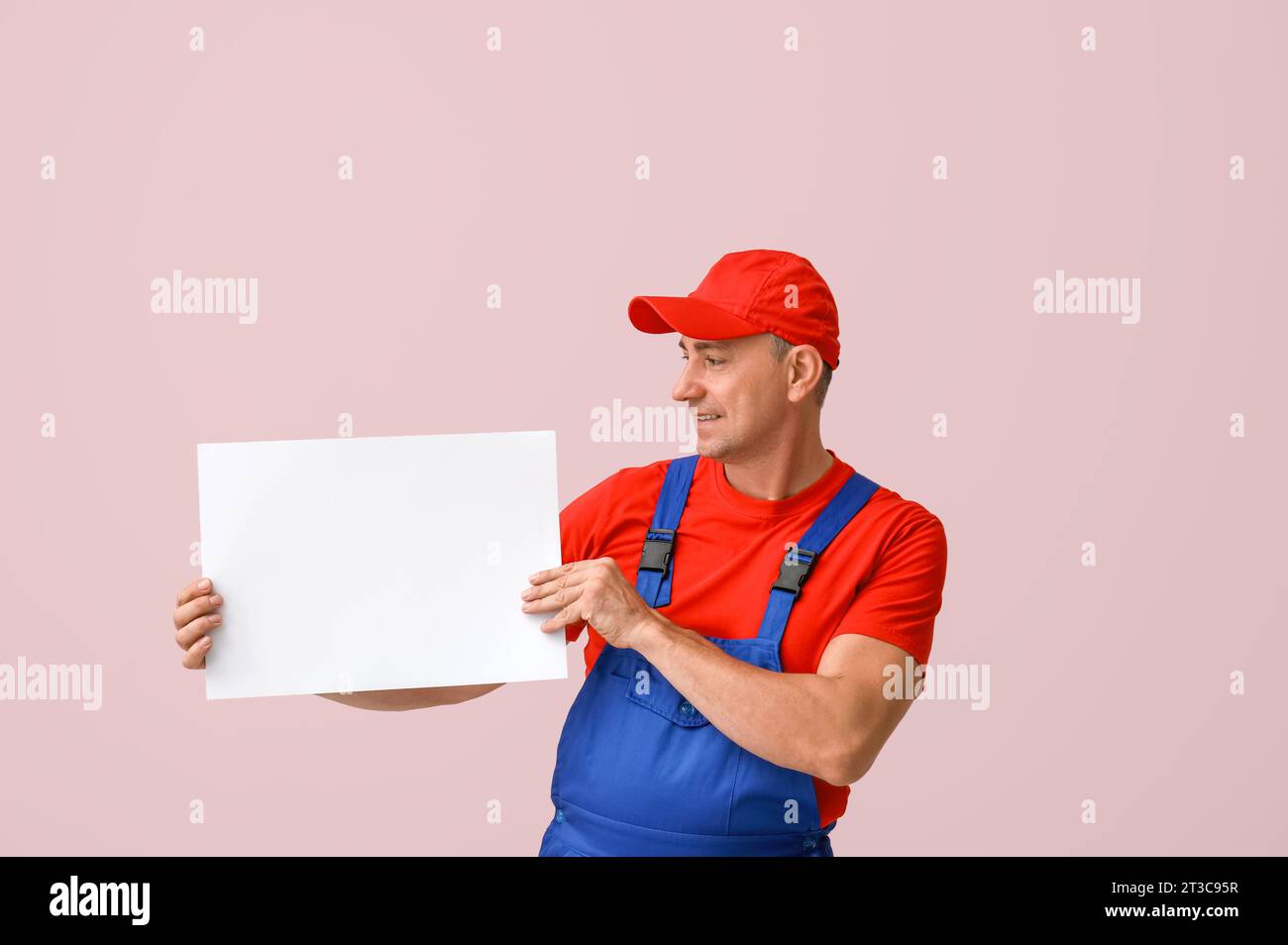 Portrait of male mechanic with blank poster on pink background Stock ...