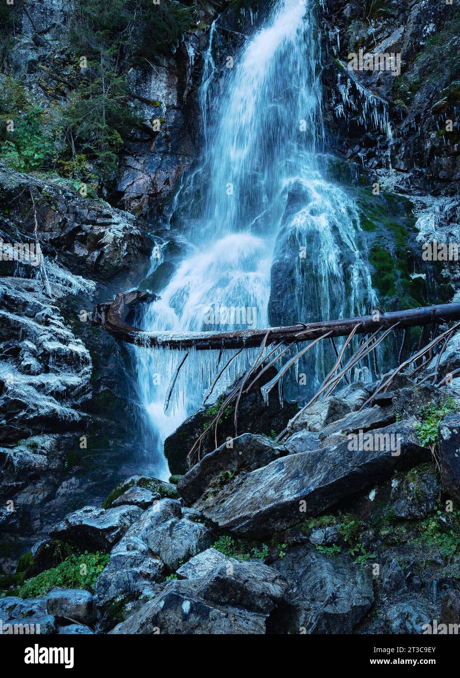 nature background a tall waterfall cascading down around frozen rocks ...
