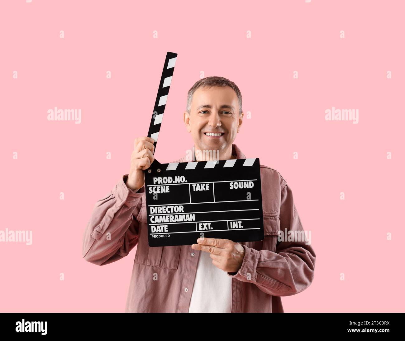 Mature actor with movie clapper on pink background Stock Photo - Alamy