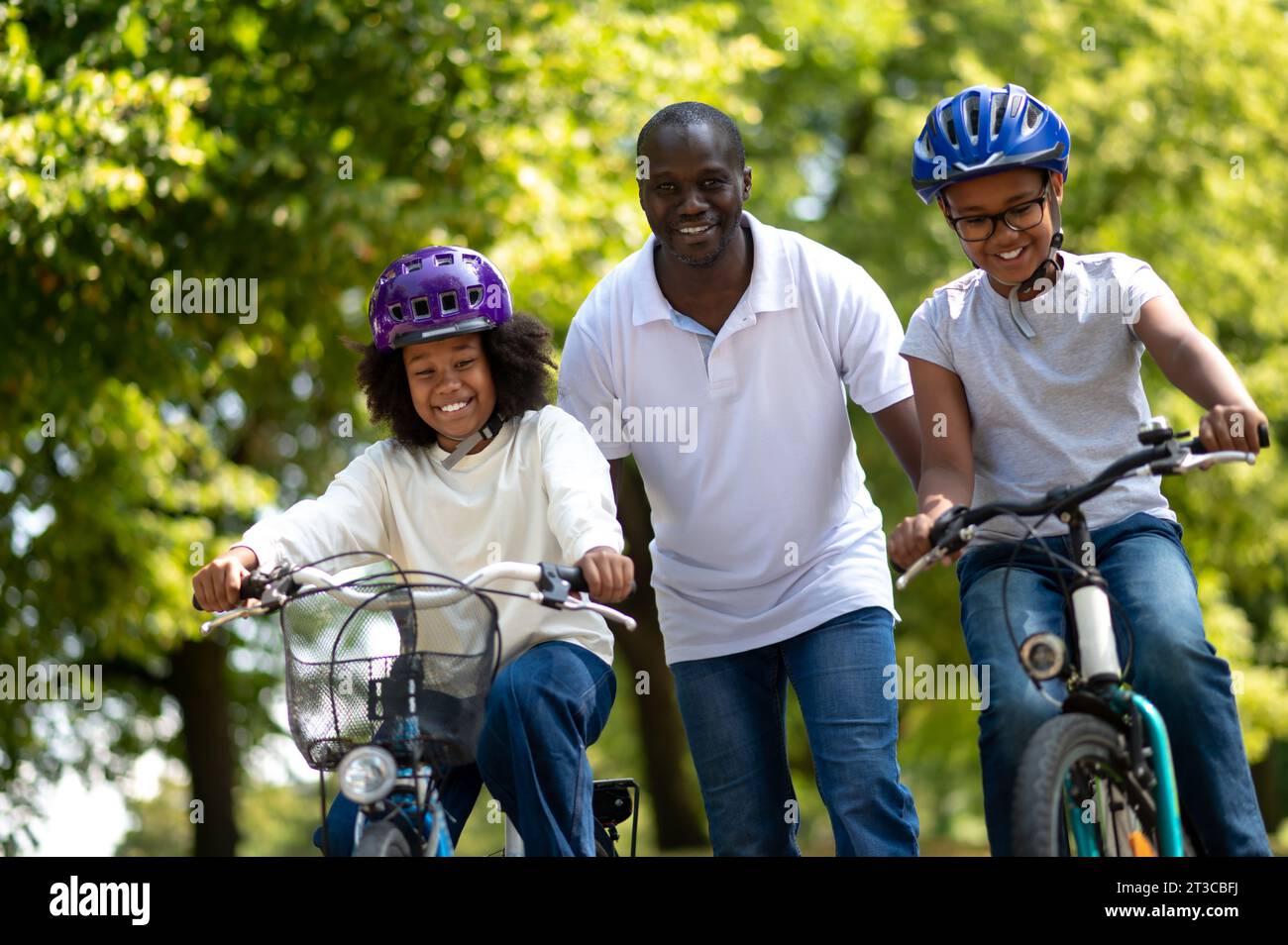 Father teaching his kids riding a bike and looking happy Stock Photo ...