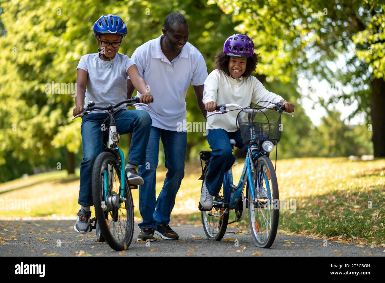 Father teaching his kids riding a bike and looking happy Stock Photo ...
