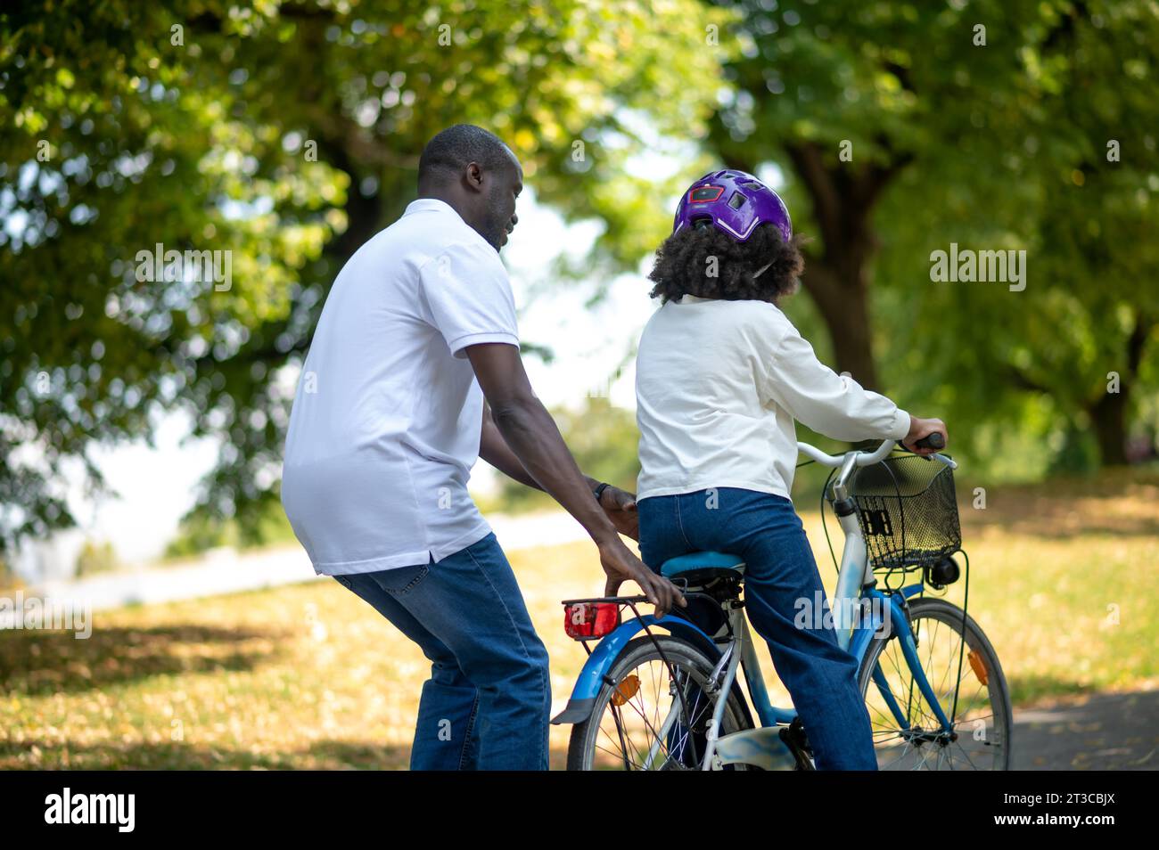 Father teaching his kids riding a bike and looking happy Stock Photo ...