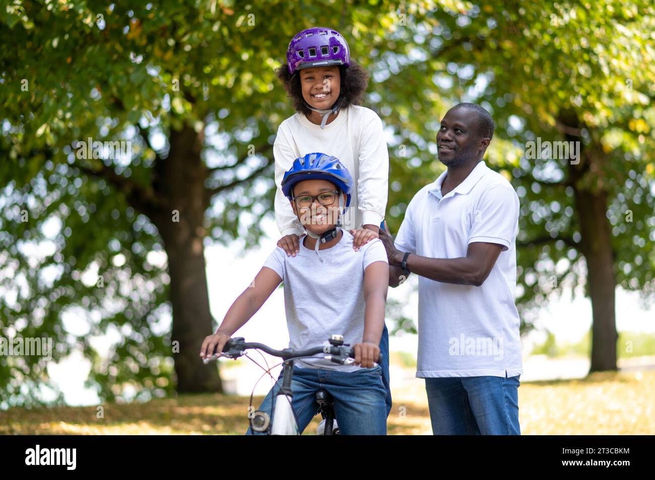 Happy family riding a bike in a park and having fun together Stock ...