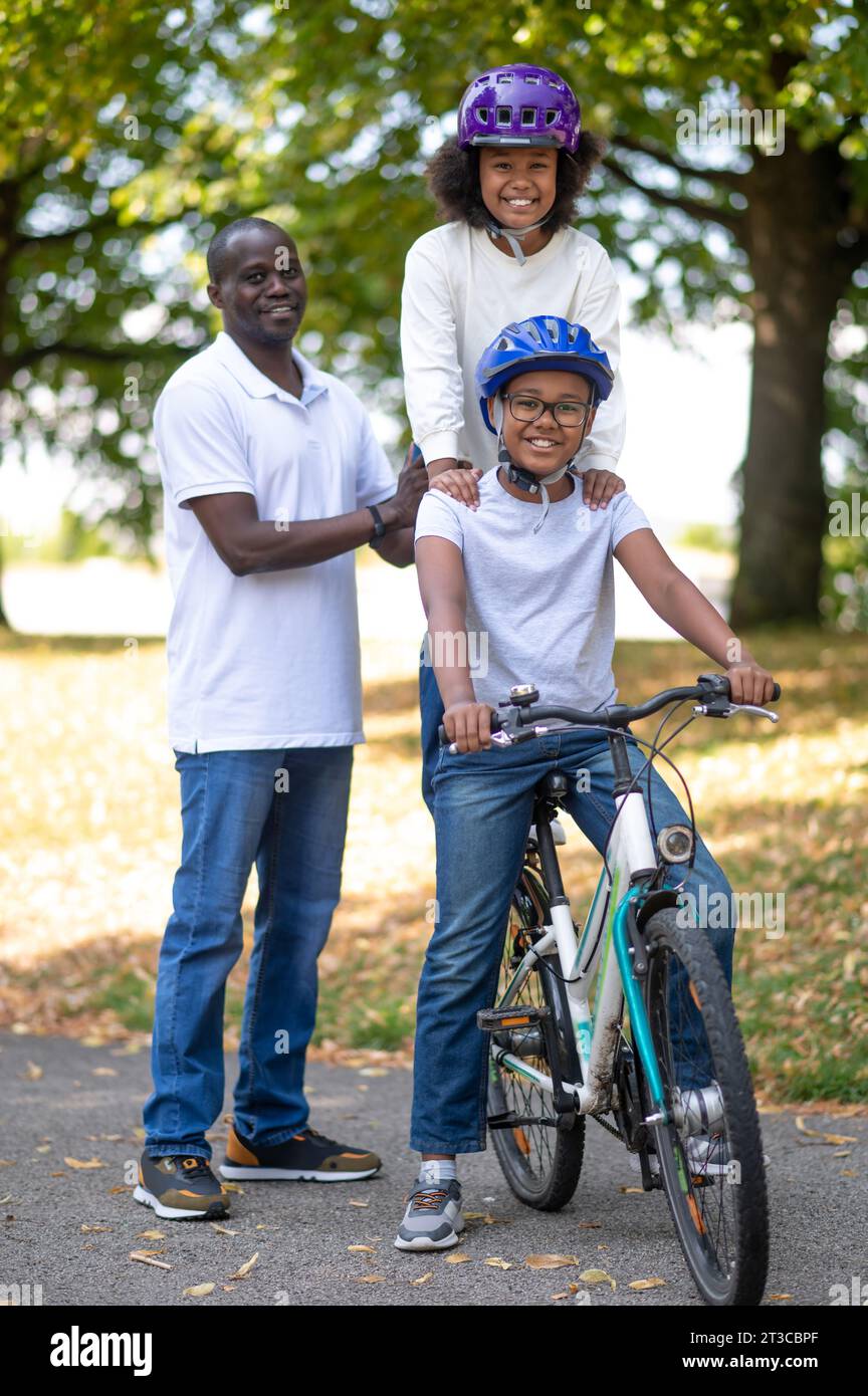 Happy family riding a bike in a park and having fun together Stock ...