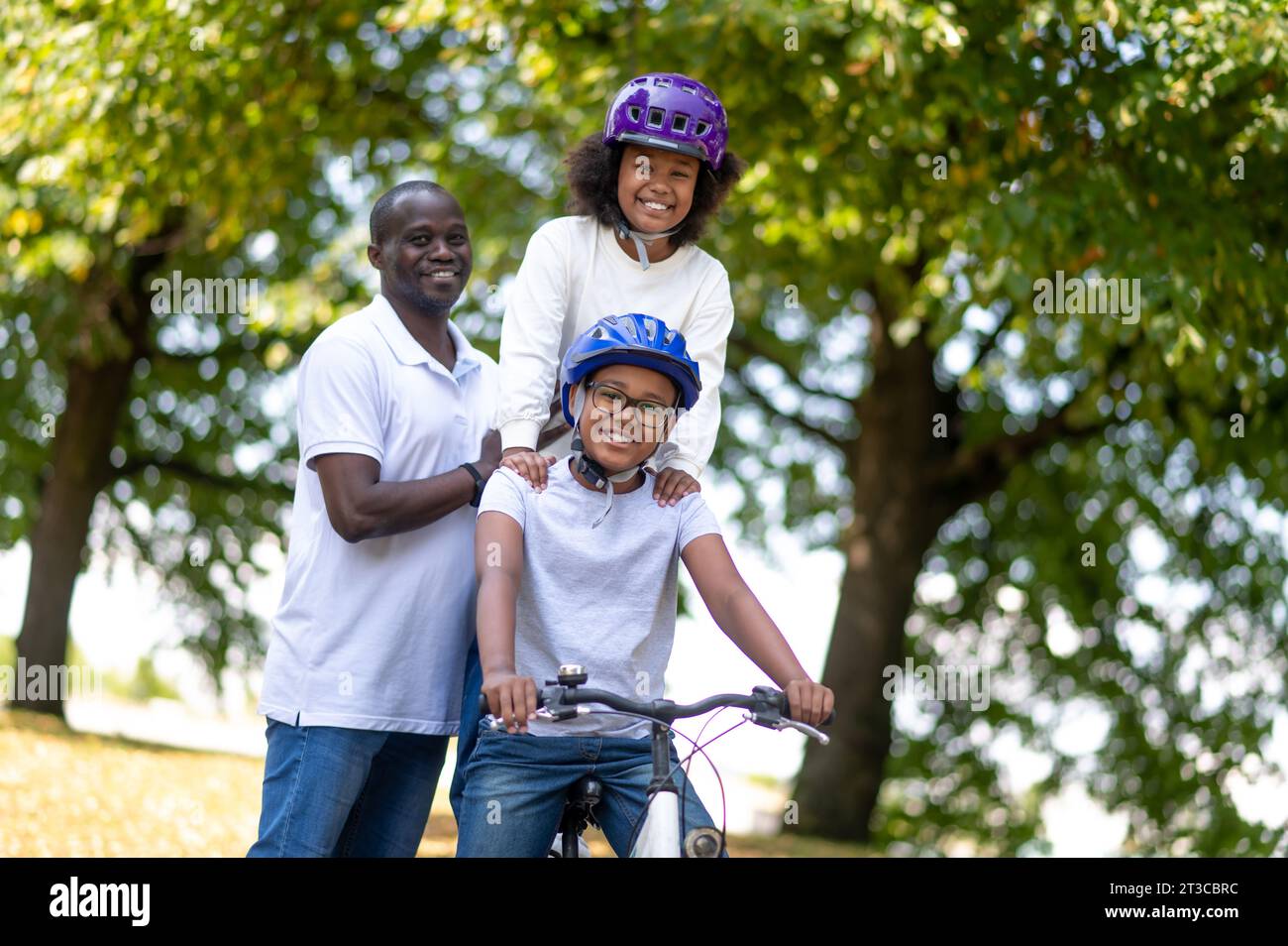 Happy family riding a bike in a park and having fun together Stock ...