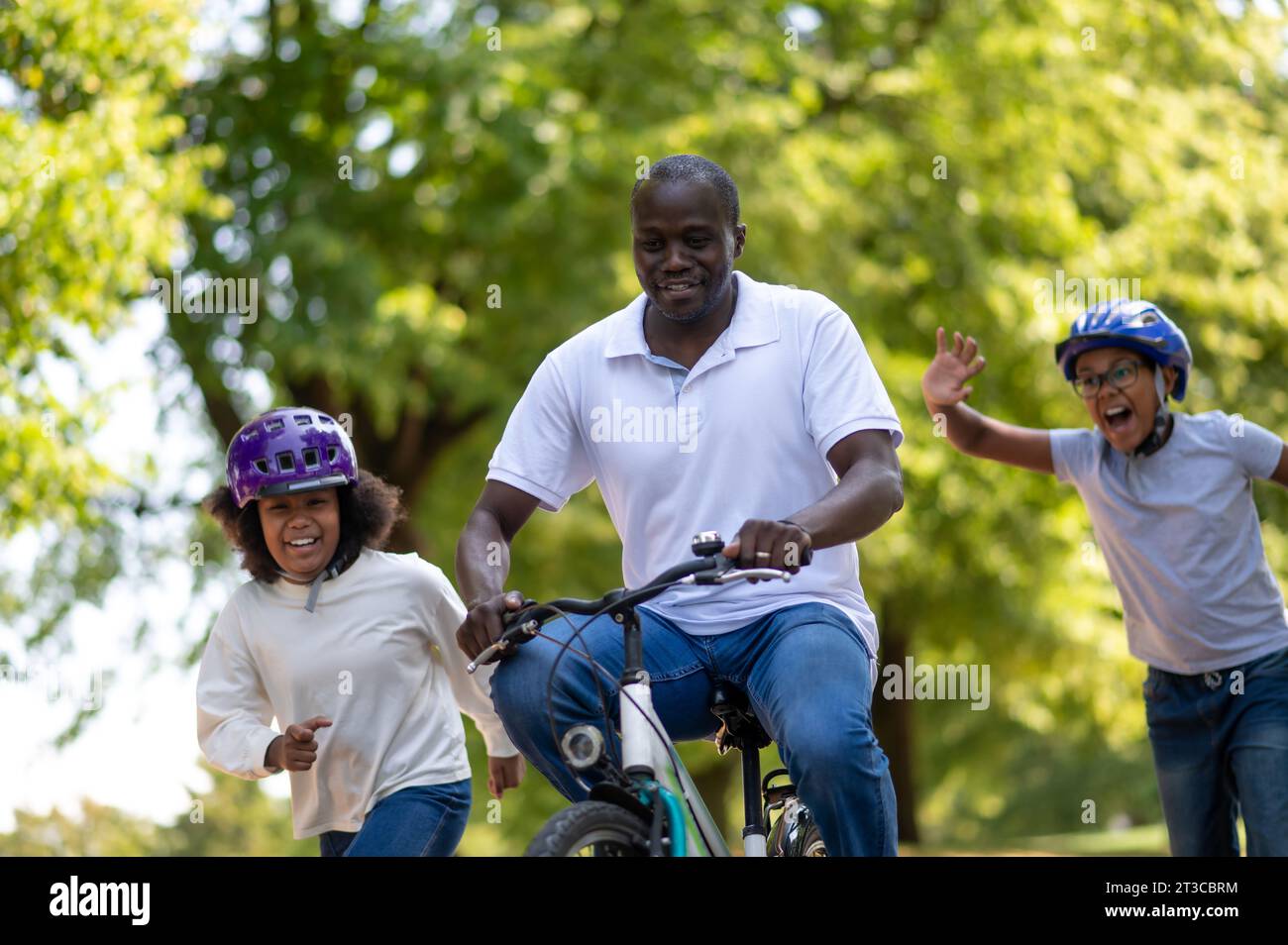 African american man riding a bike and having fun with his kids Stock ...
