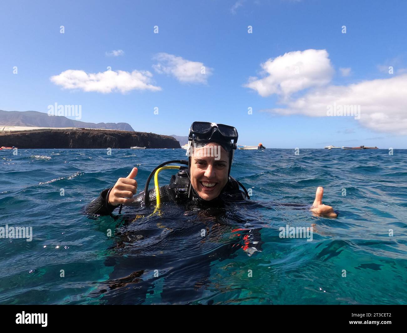 Diver woman floating on the water surface smiling with thumbs up after ...