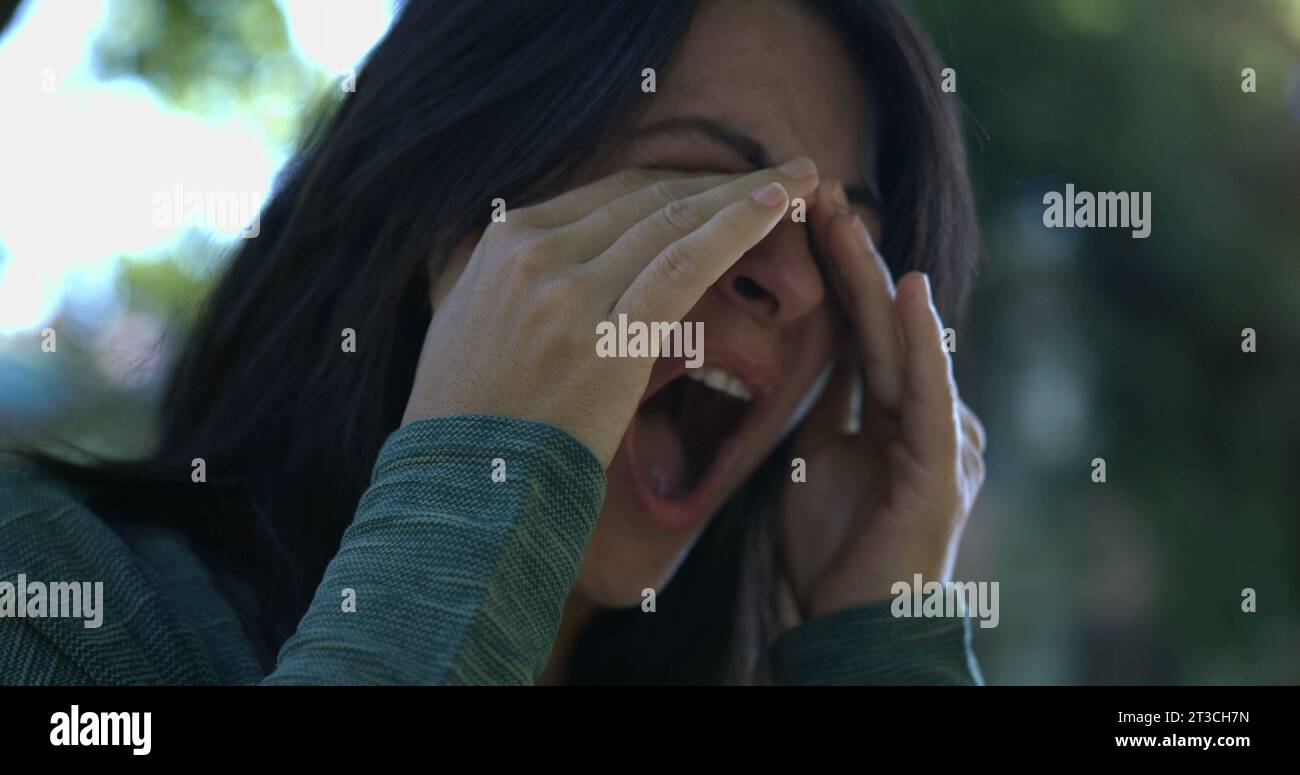 Tired woman yawning and rubbing eyes and face with hands standing ...
