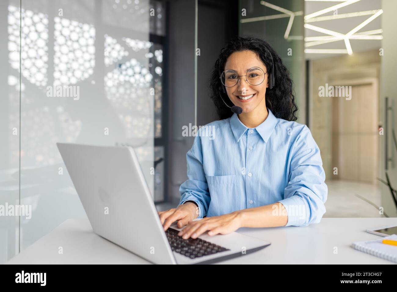 Portrait of successful woman helpline worker, using headset phone for ...