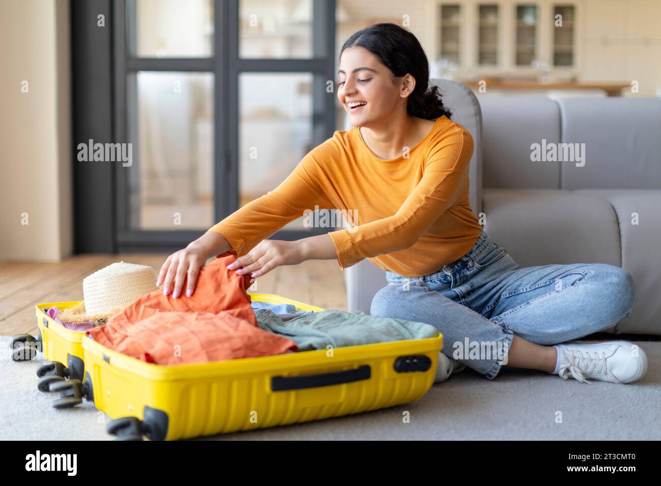 Getting Ready For Travel. Cheerful young indian woman packing suitcase ...