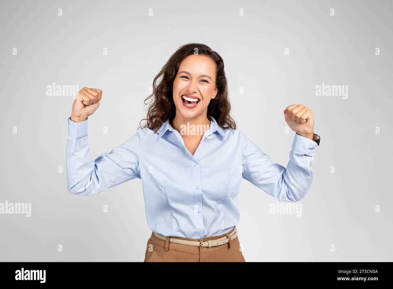 Exuberant young European woman celebrating a win, fists pumped up in ...