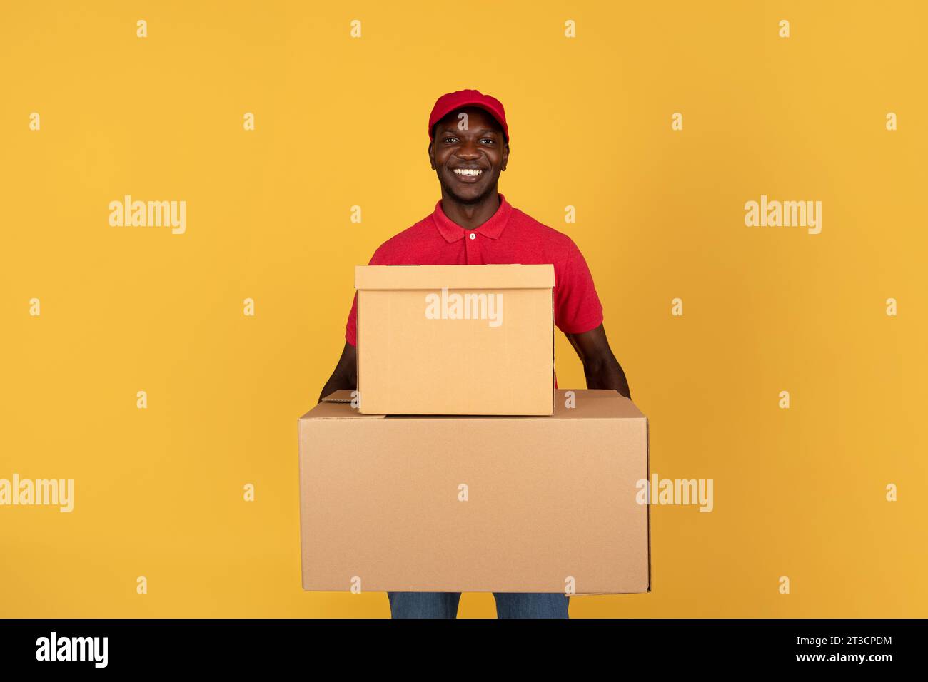 Glad handsome millennial black guy courier in red uniform hold many big ...
