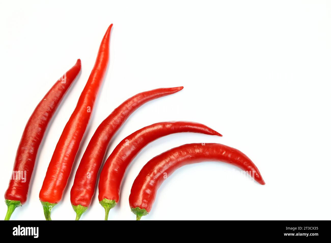 Red chillies arranged against a white background. The image crop has ...