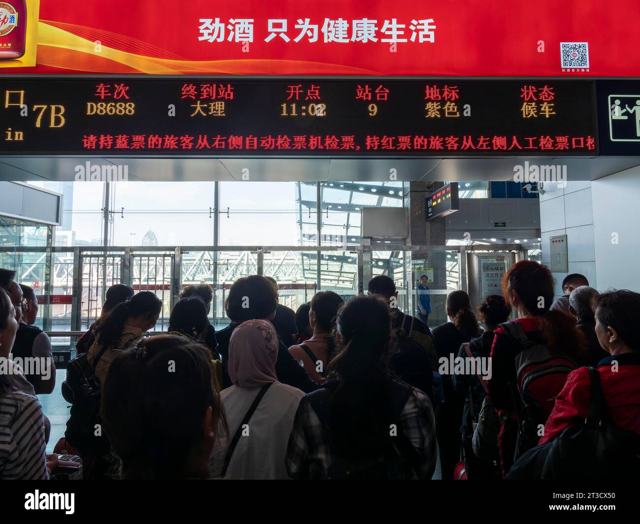 Waiting passers-by in railway station, Chinese ticker, Kunming, Yunnan ...
