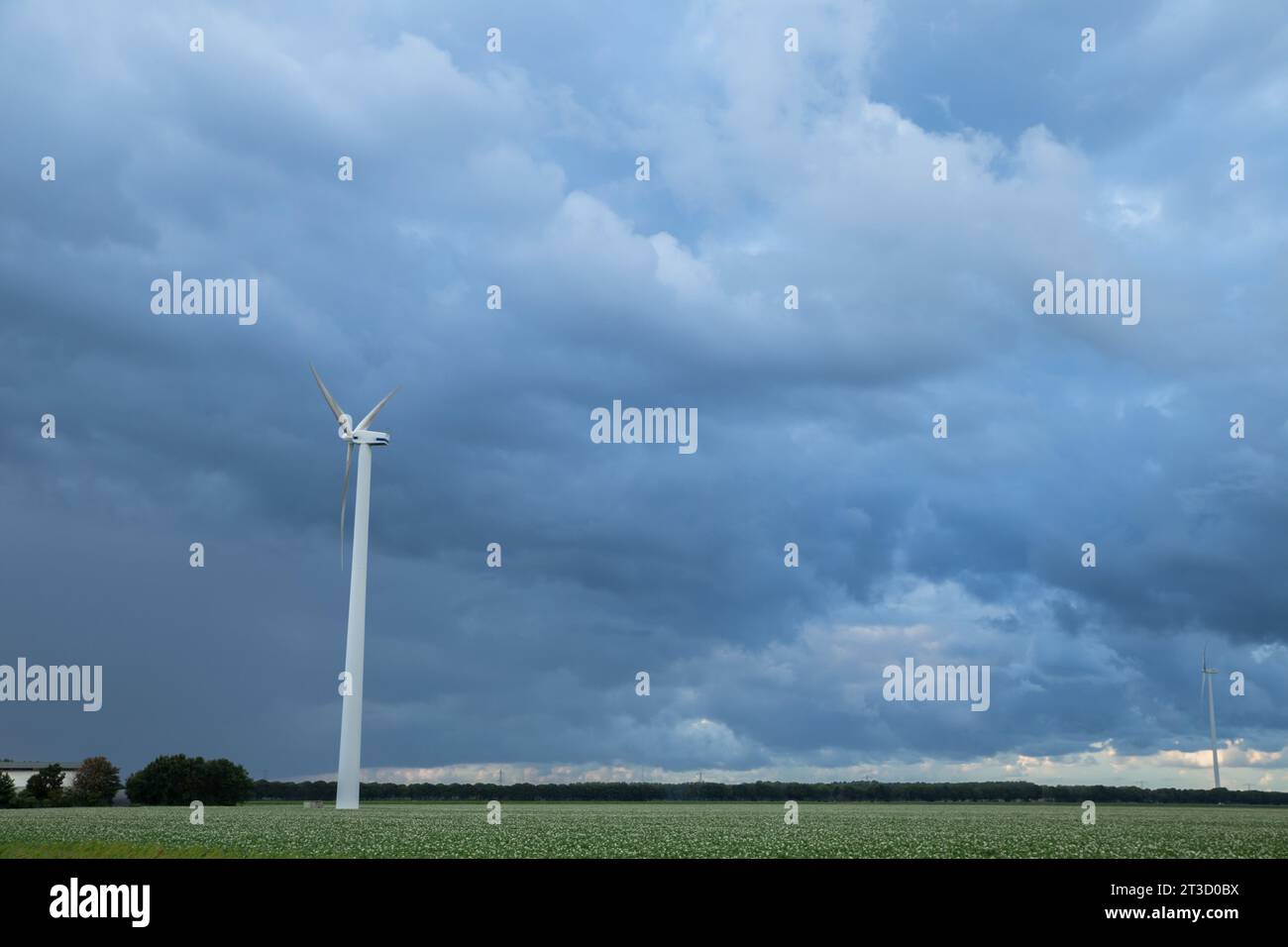 two wind turbine stand in the farmland with cloudy sky in the ...