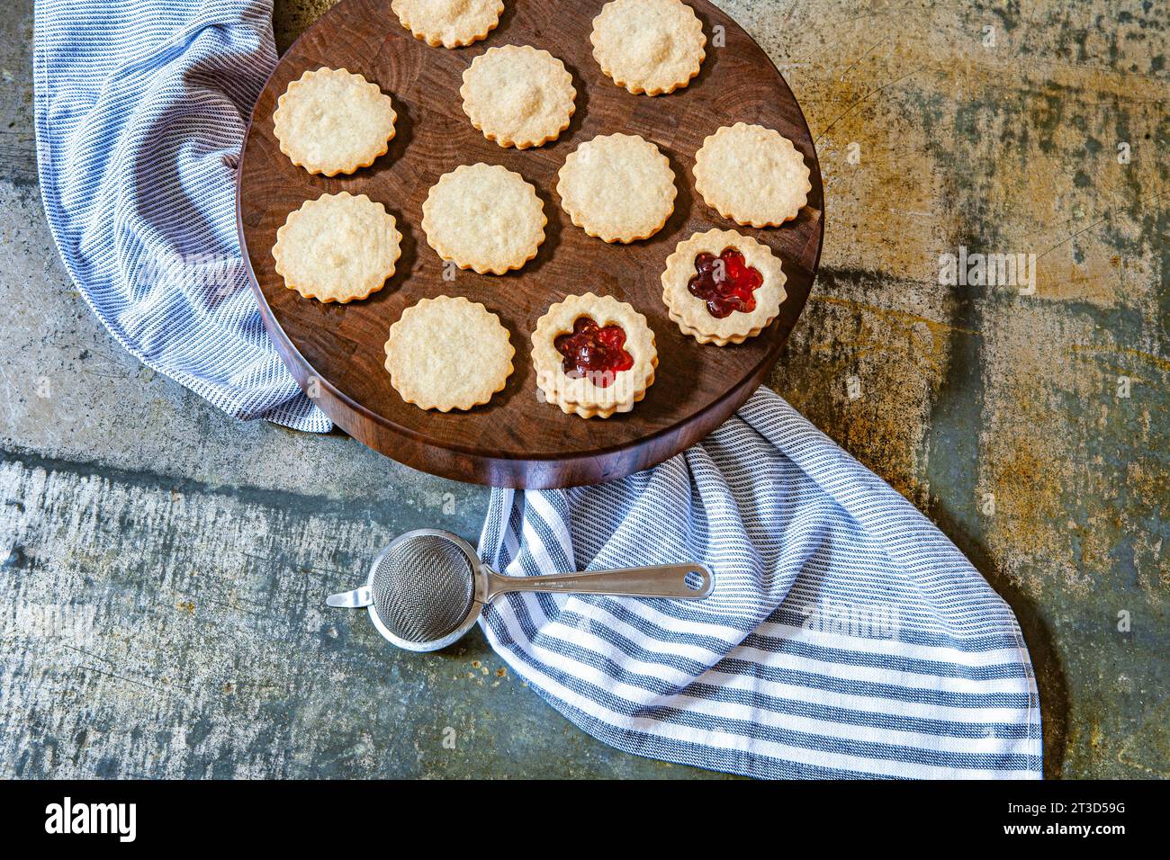High angle view of Linzer tarts being assembled on round wood board ...