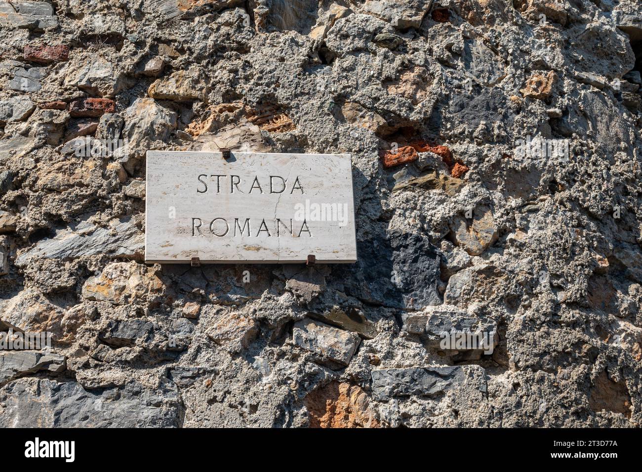 Street sign that says: "Strada Romana" (Roman Road) on an ancient stone ...