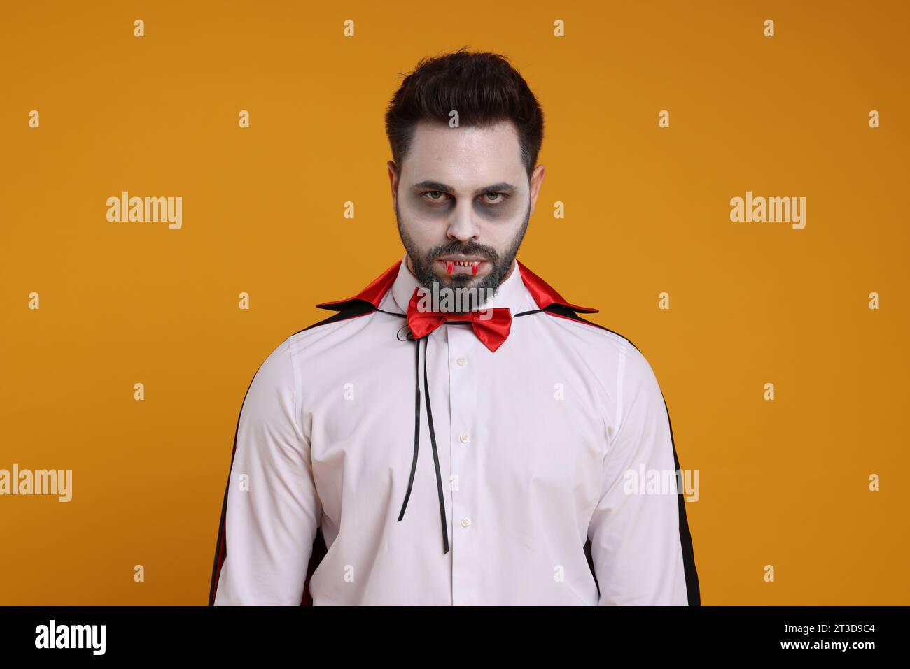 Man in scary vampire costume with fangs on orange background. Halloween ...