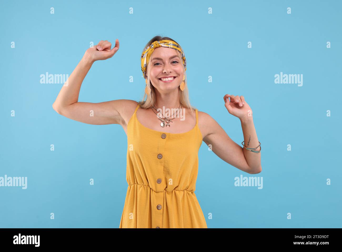 Portrait of smiling hippie woman dancing on light blue background Stock ...