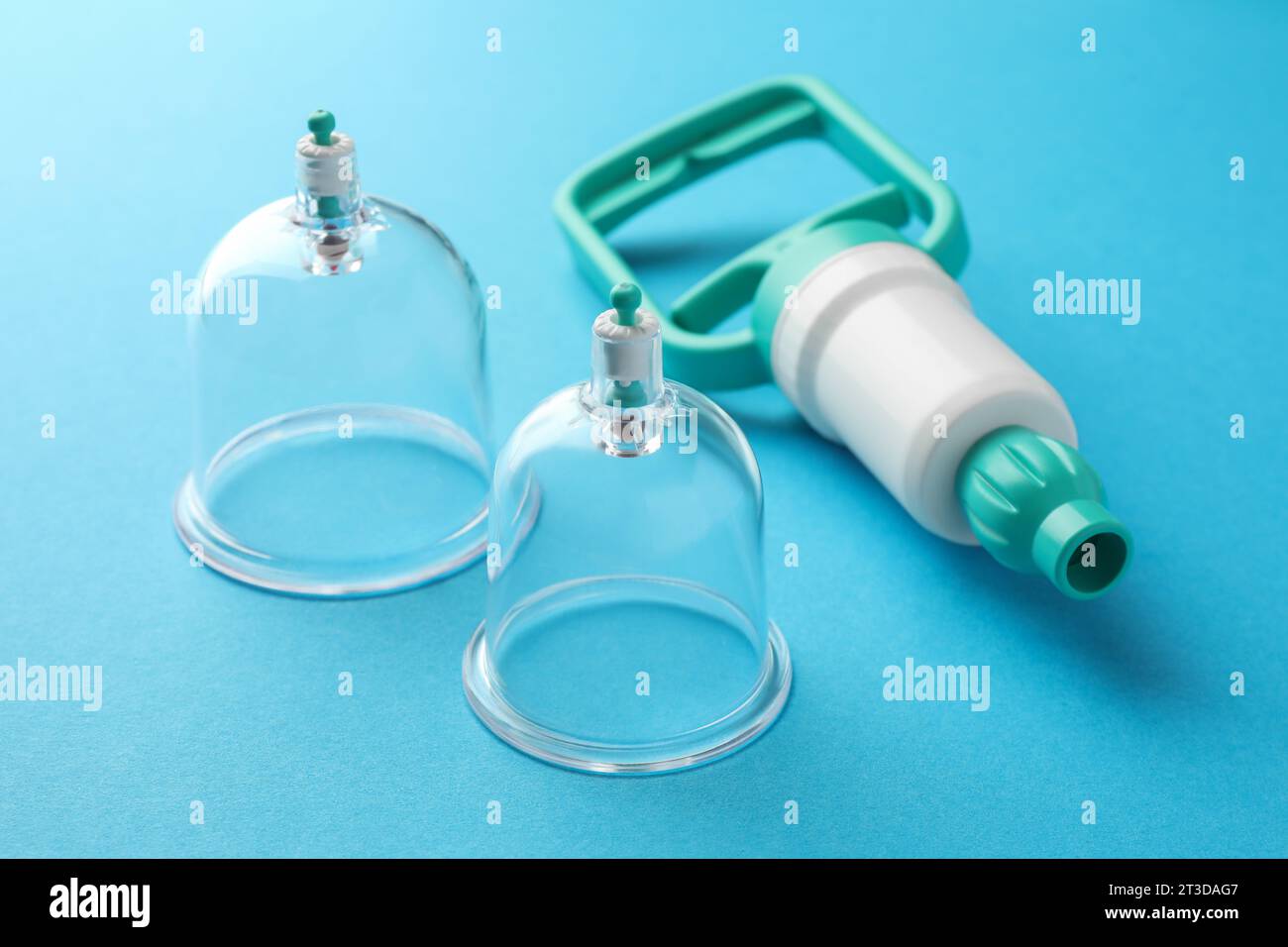 Plastic cups and hand pump on light blue background. Cupping therapy ...