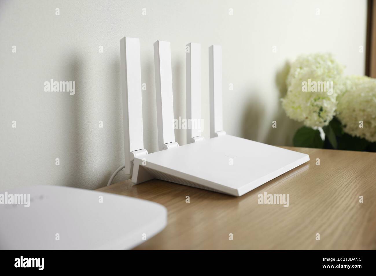New modern Wi-Fi router on wooden table near white wall Stock Photo - Alamy