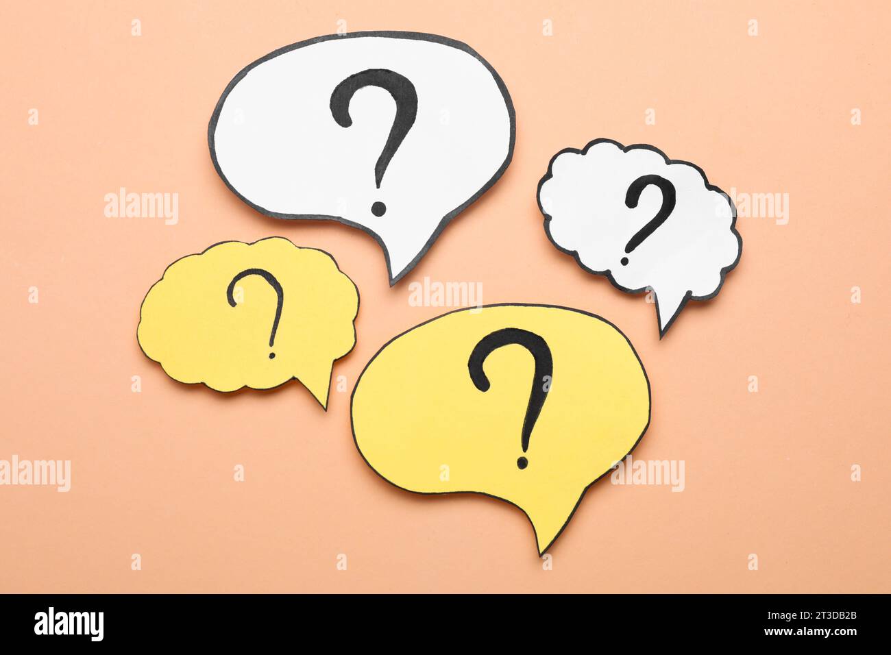 Paper speech bubbles with question marks on beige background, flat lay ...