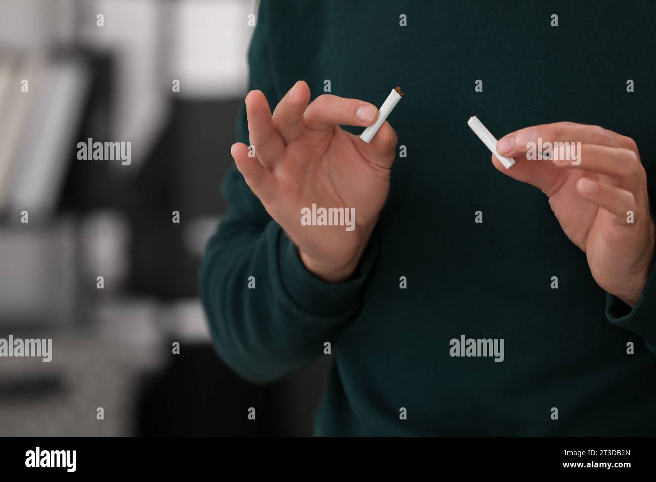 Stop smoking concept. Man holding pieces of broken cigarette on blurred ...