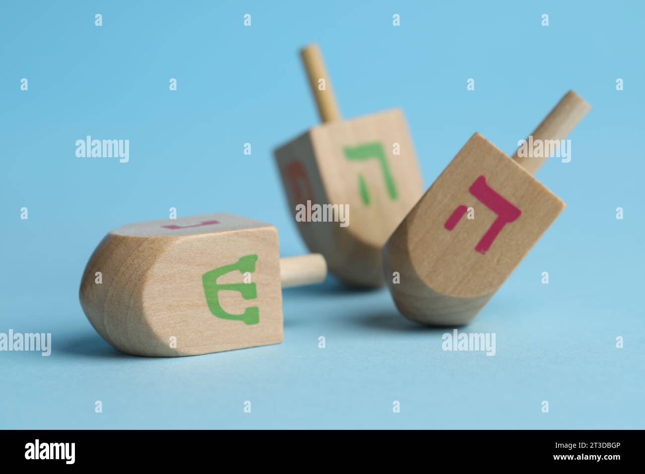 Wooden dreidels on light blue background. Traditional Hanukkah game ...