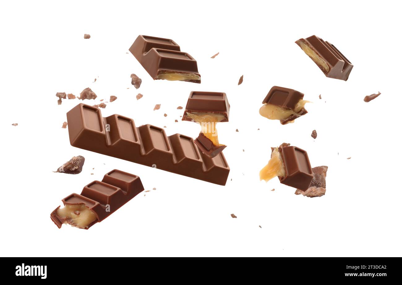 Whole and broken chocolate bars with caramel falling on white ...