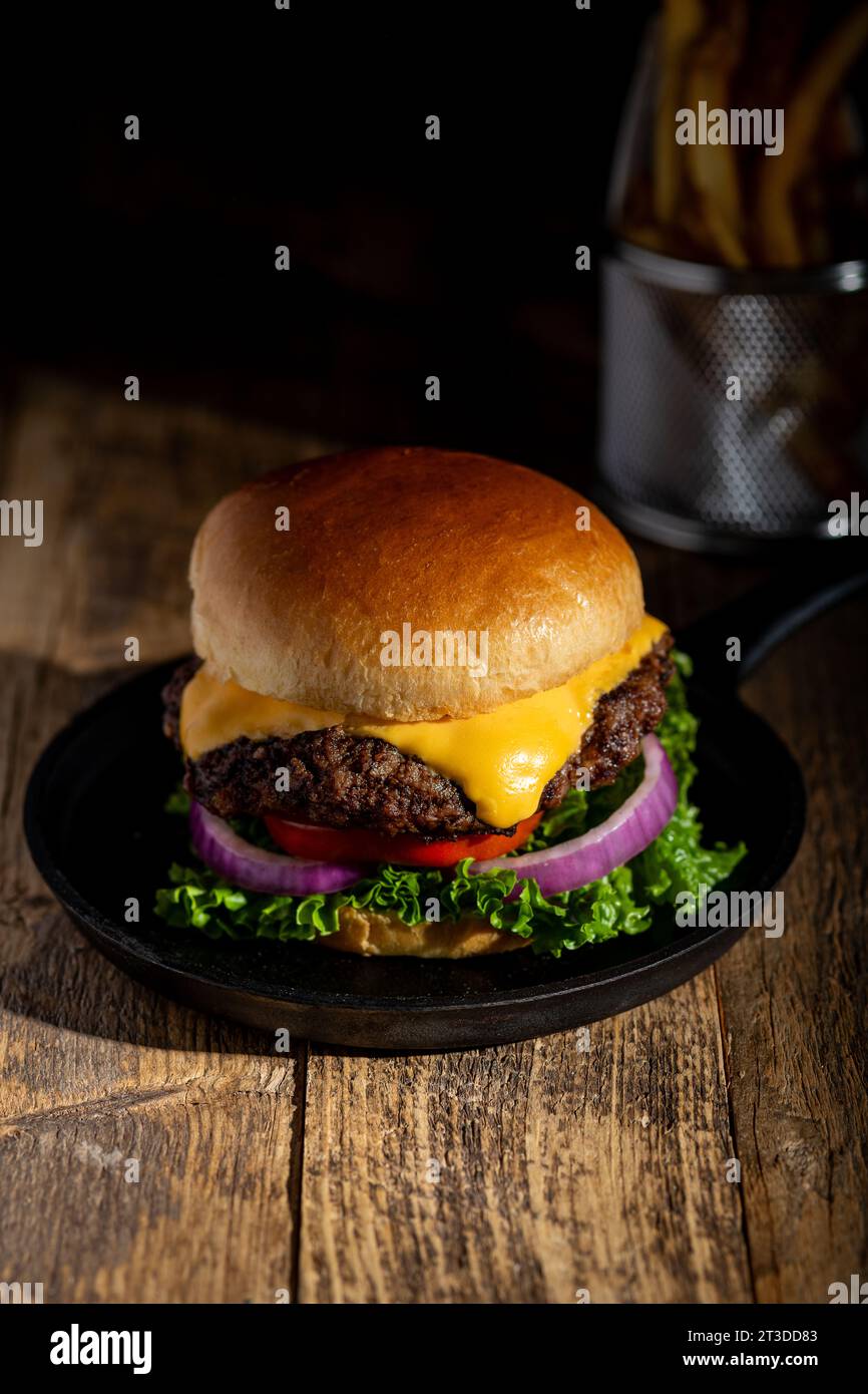 Hot Cheeseburger with melting cheese, lettuce, tomato on a brioche bun ...