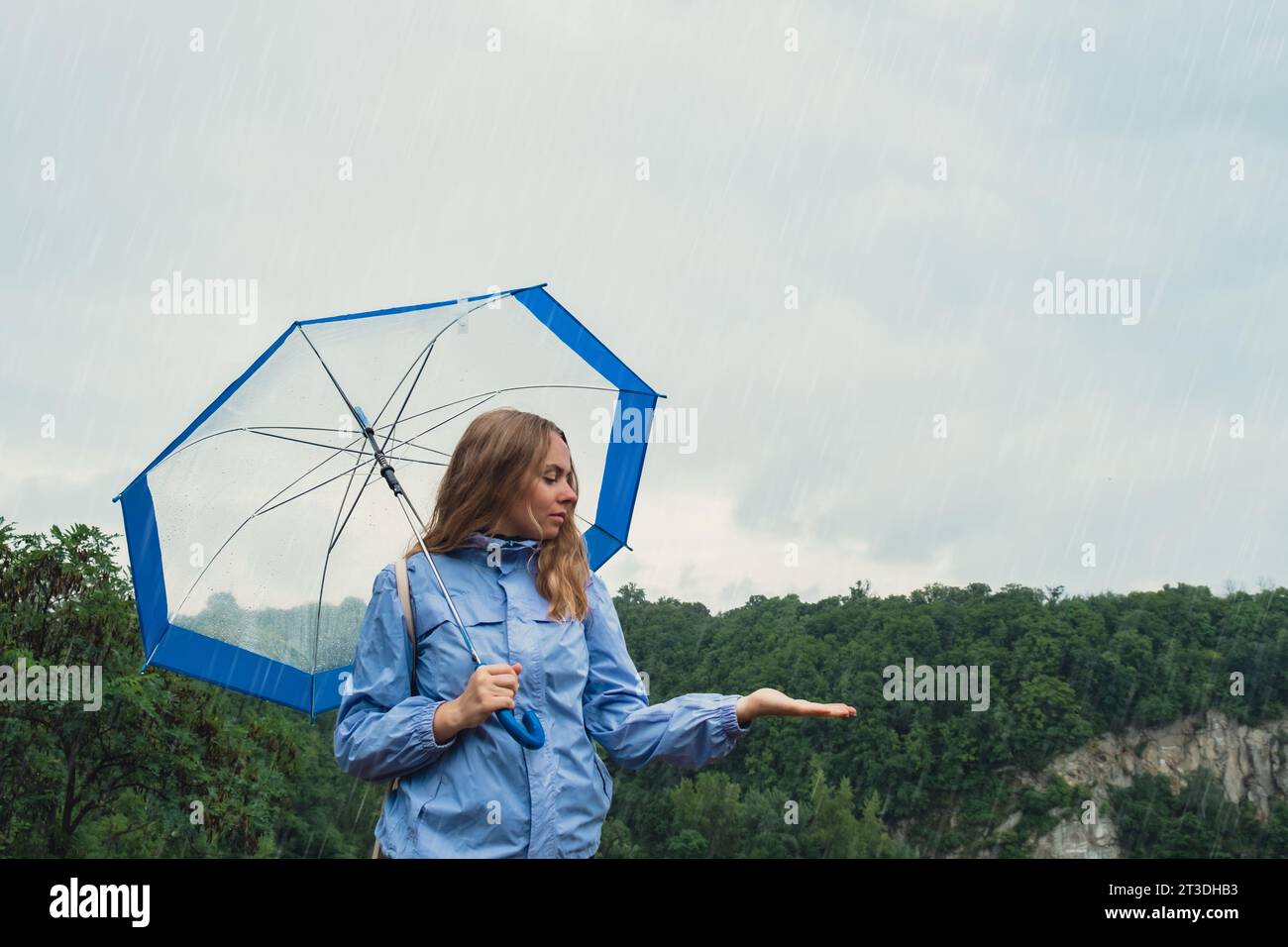 Blonde girl checking the weather under transparent umbrella outside in ...