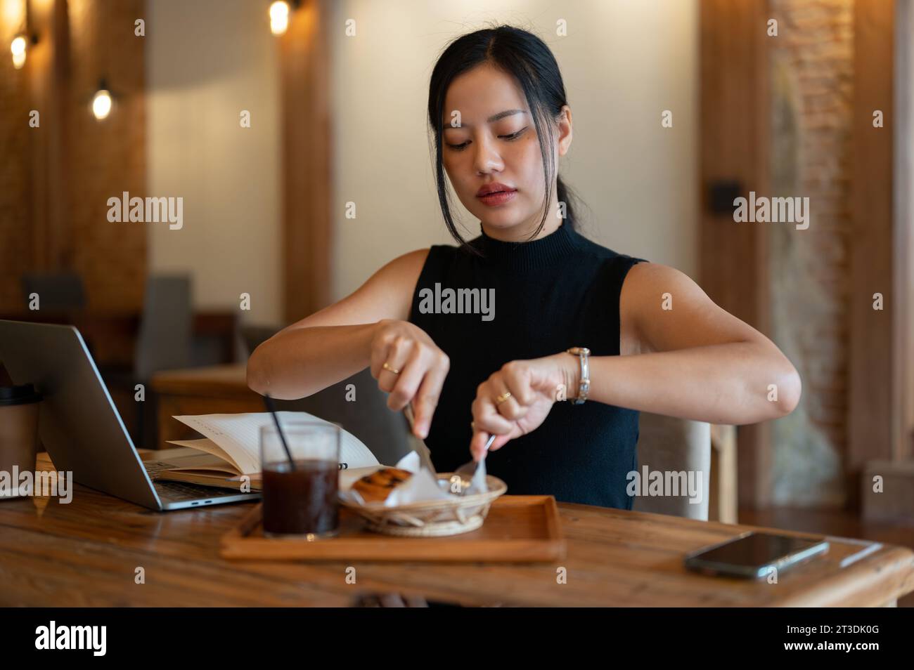 A gorgeous millennial Asian woman is having breakfast while working ...