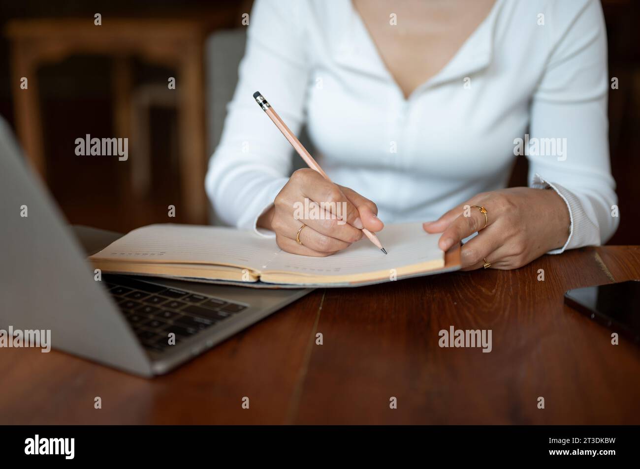 Cropped image of a woman writing some ideas down in her book, working ...