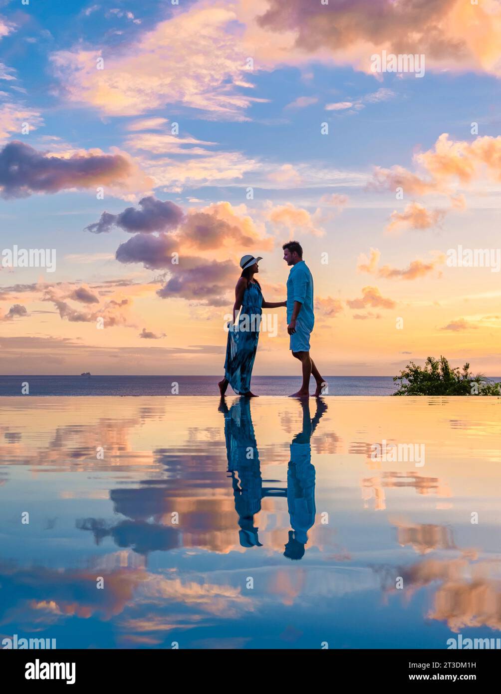 Young men and women watching the sunset with reflection in the infinity ...