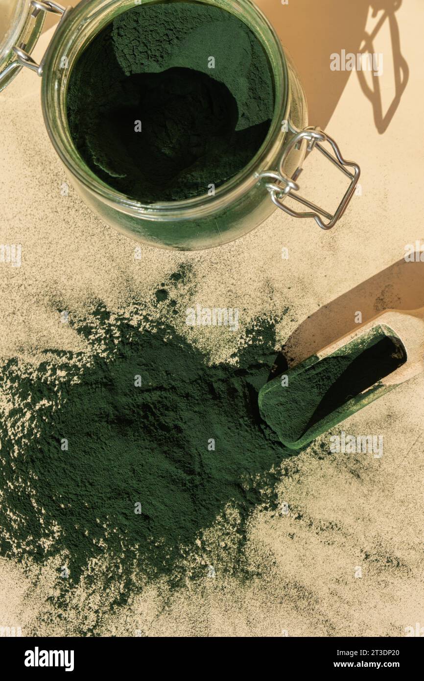 Organic blue-green algae spirulina powder food in glass jar with wooden ...