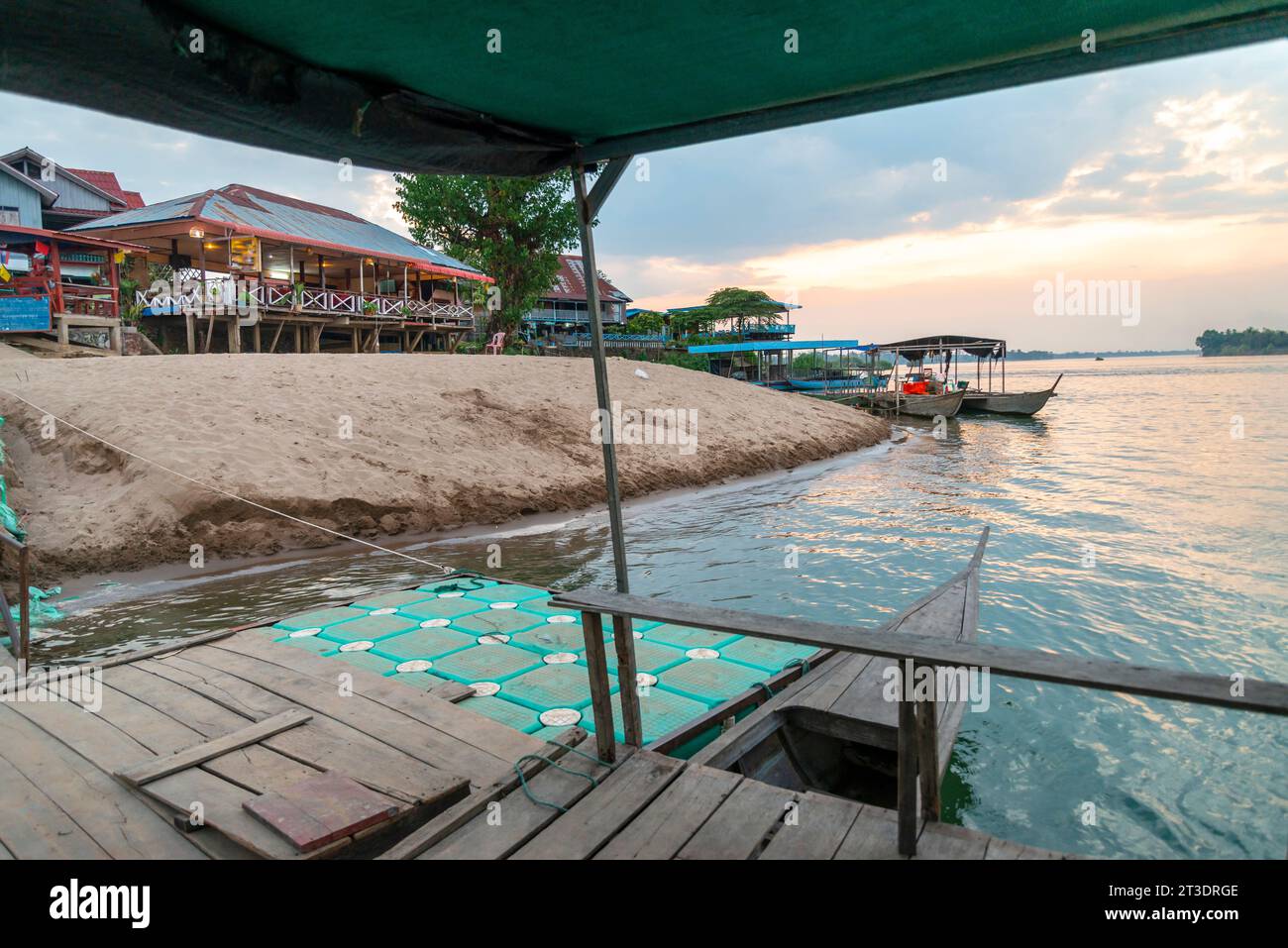 At sunset,on the Mekong river,small wooden boats ferrying travelers to and from Nakasong and Don ...