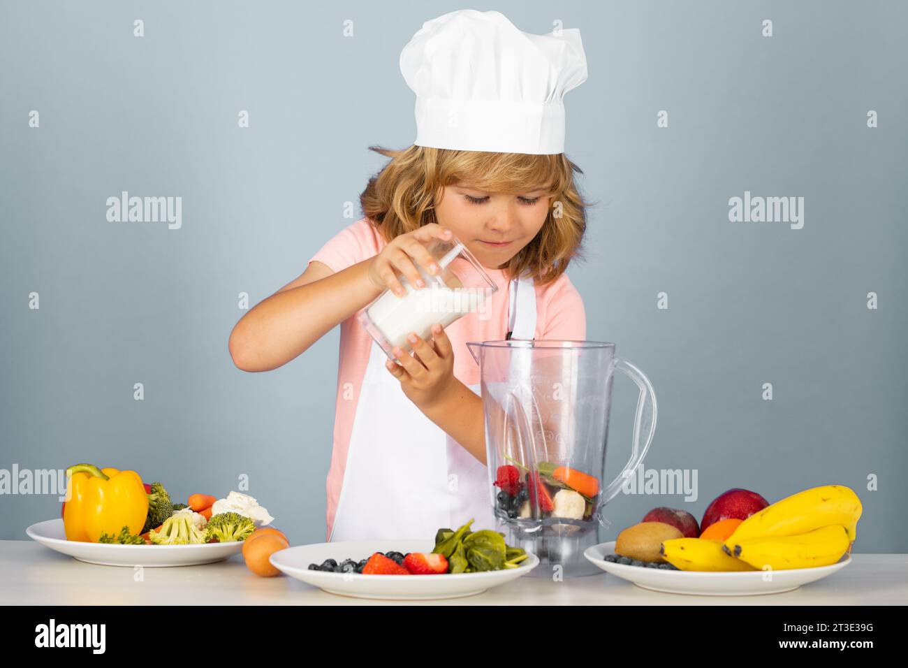 Portrait of chef child in cook hat make milk shake smoothie. Cooking at ...