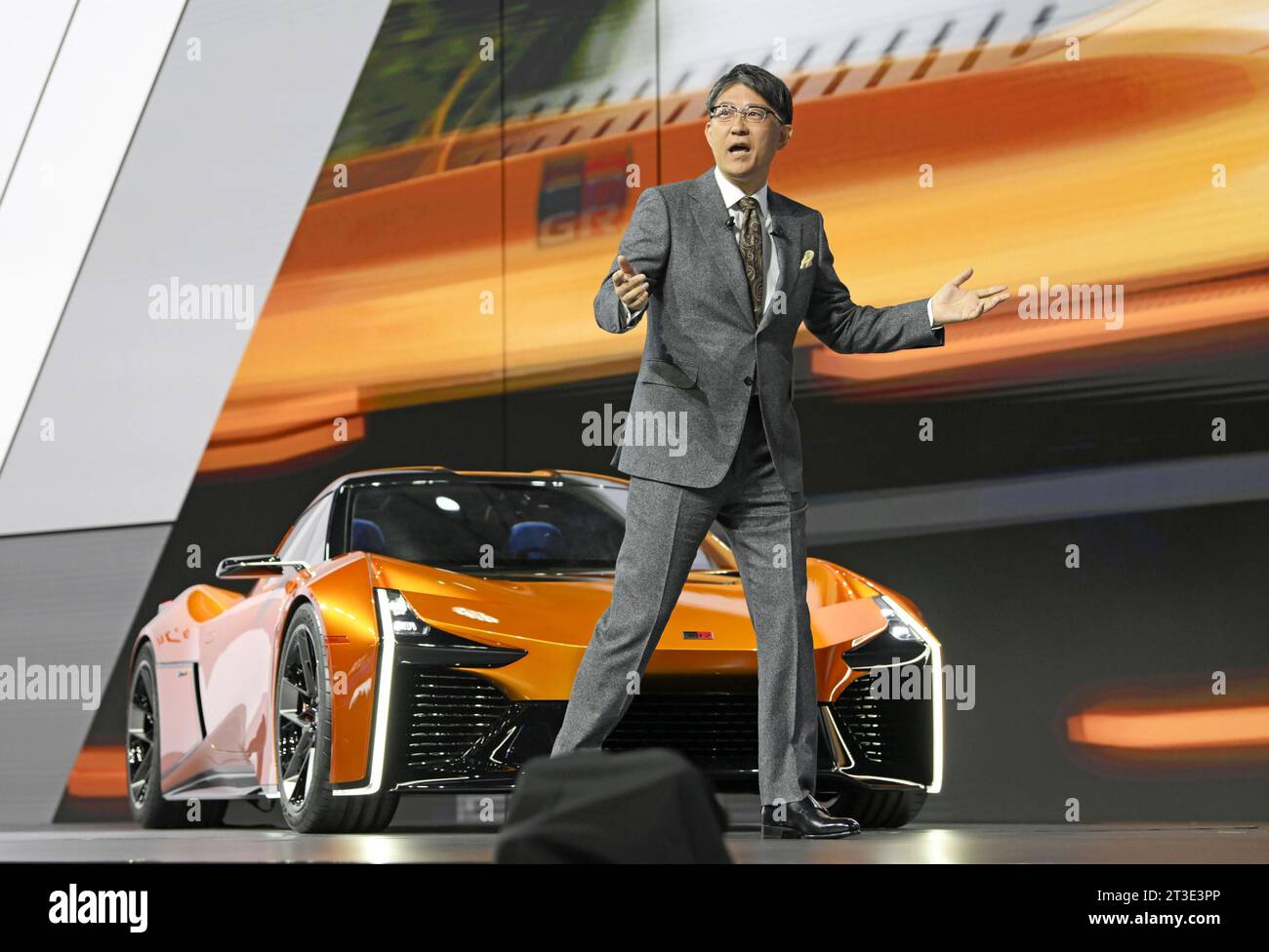 Toyota Motor Corp. President Koji Sato speaks on stage next to a ...