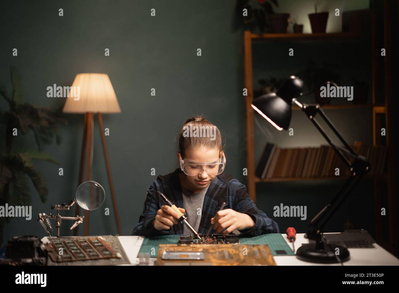 Girl spends time repairing the motherboard, soldering electronics ...