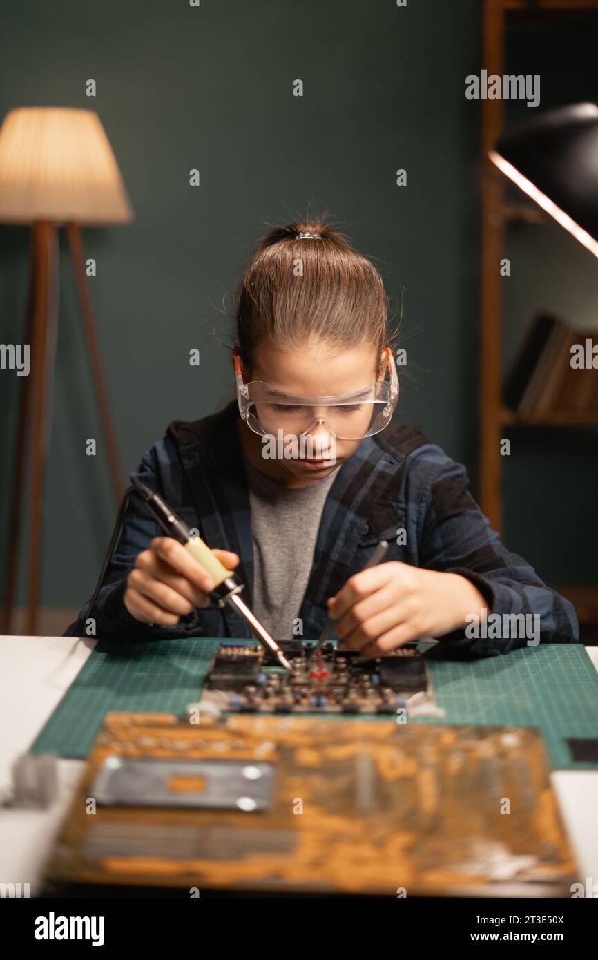 Teenage girl soldering motherboard in home workshop doing her favorite ...
