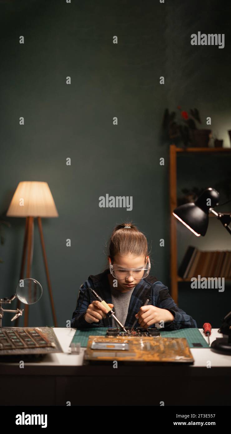 Teenage girl soldering motherboard in home workshop doing her favorite ...