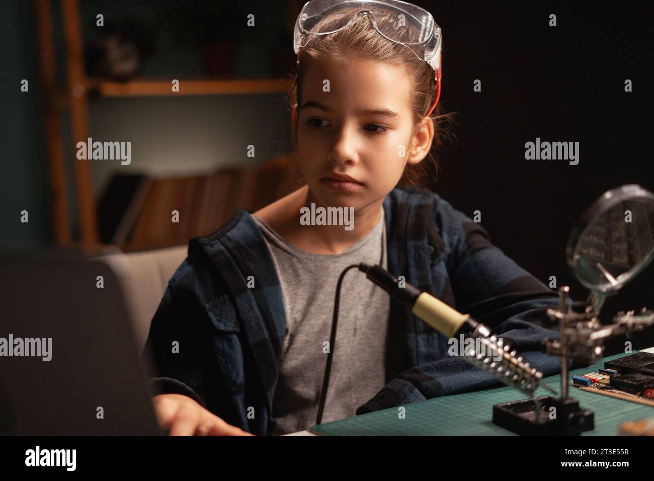Smart young teenage girl is studying soldering wires and circuit boards ...