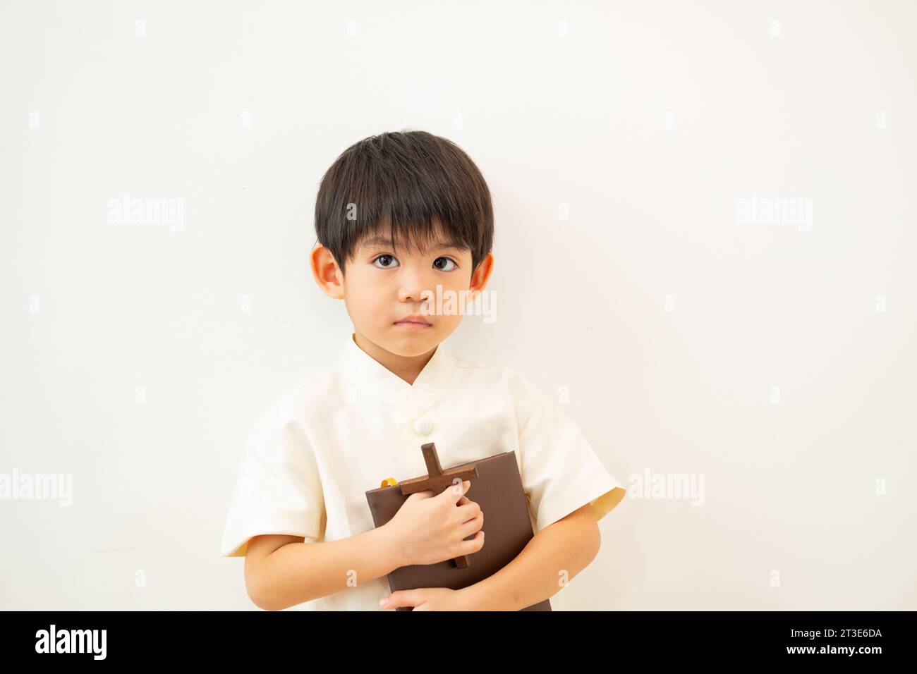 Little Asian boy prays holding a cross and a religious book, Christian ...