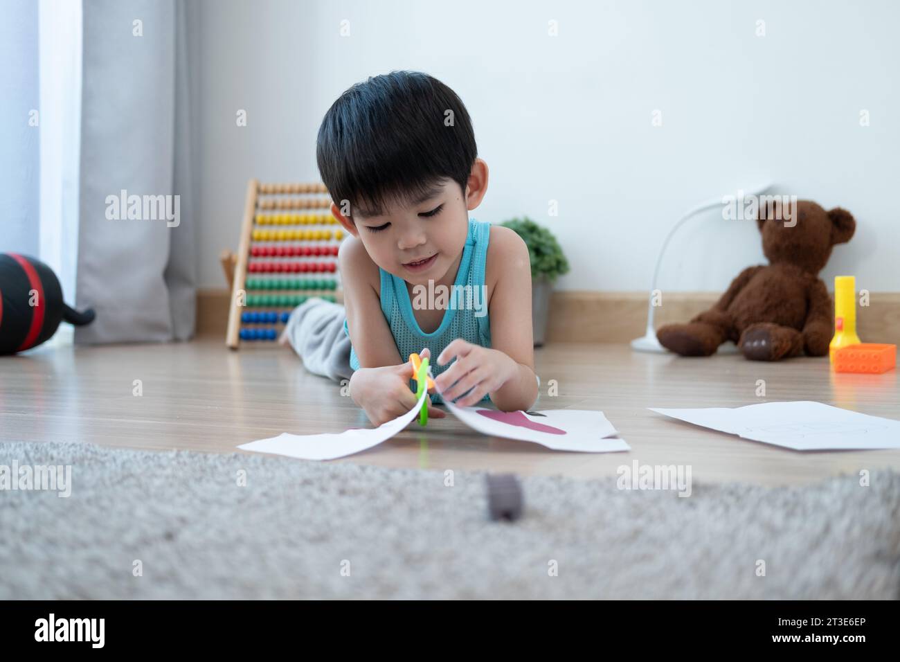 Asian boy using scissors to cut paper along lines Learning outside the ...