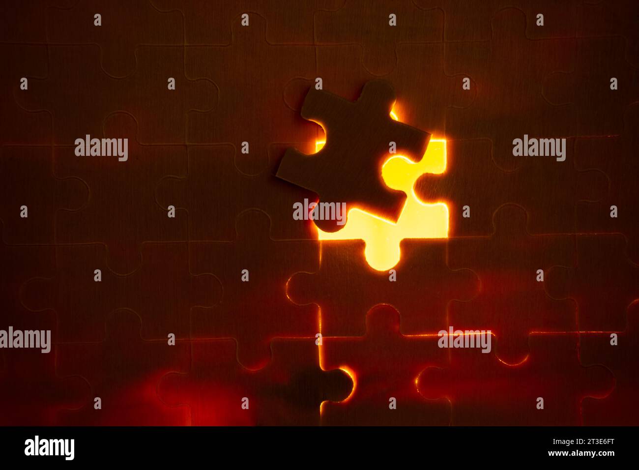 Pieces of a jigsaw puzzle filled with orange lights by hand Success ...