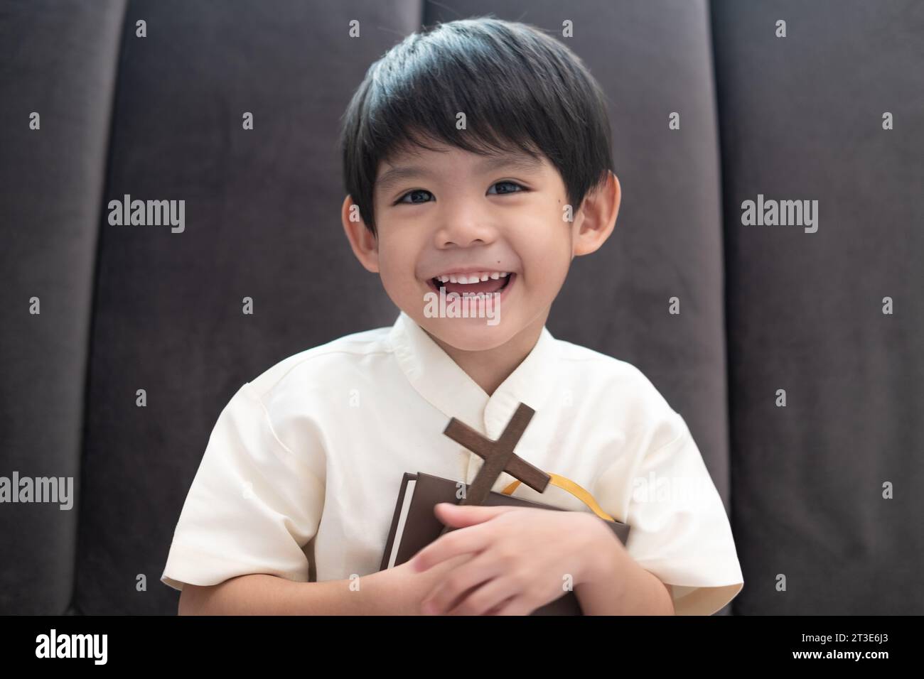Little Asian boy prays holding a cross and a religious book, Christian ...