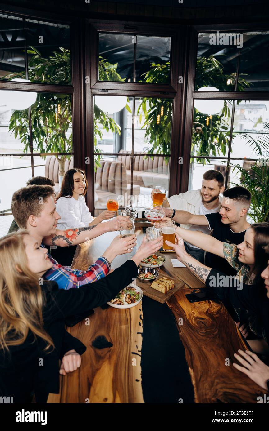 Happy group of friends drinking and clinking with beer and cocktails at ...